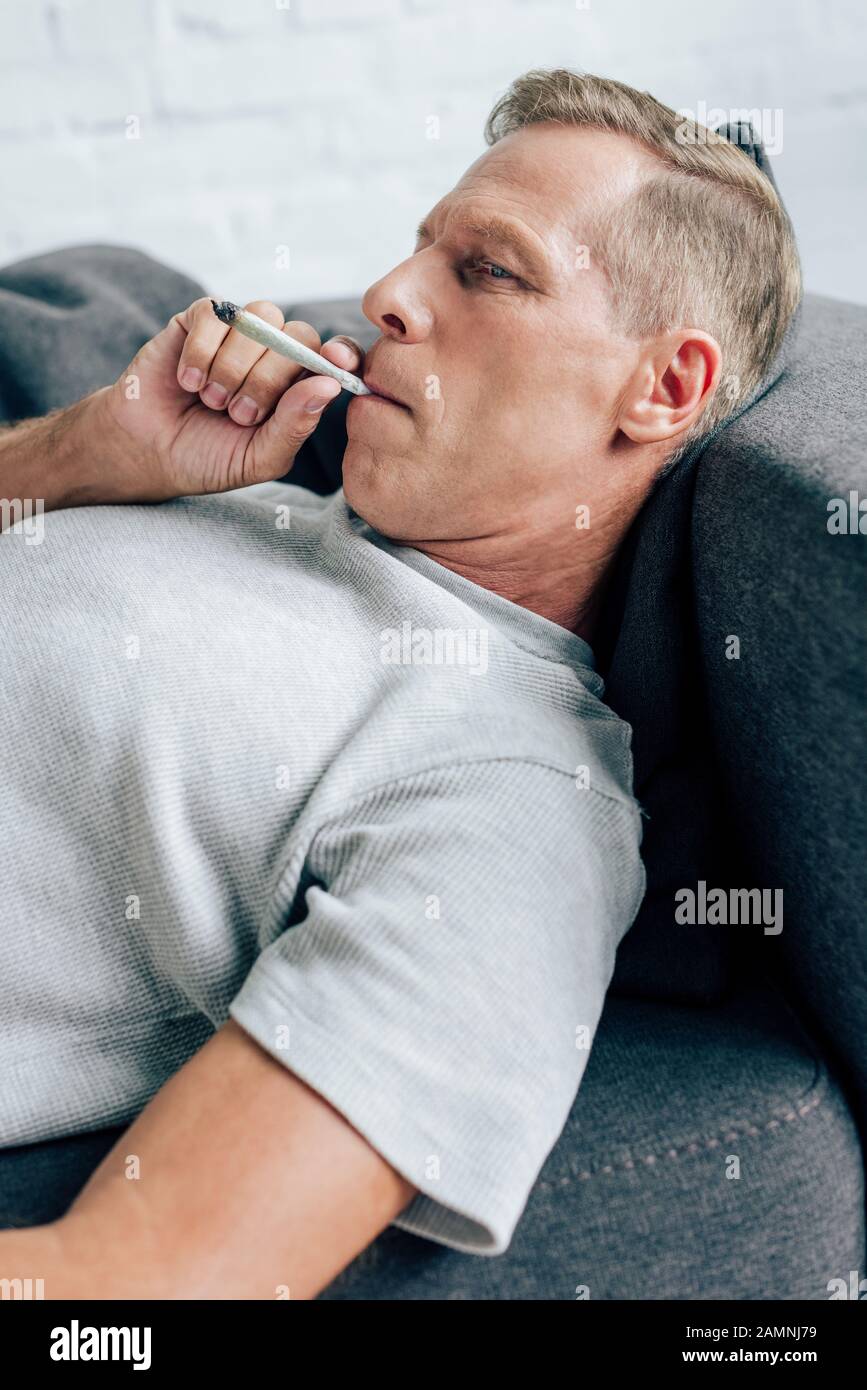 handsome man smoking blunt with medical cannabis in apartment Stock ...