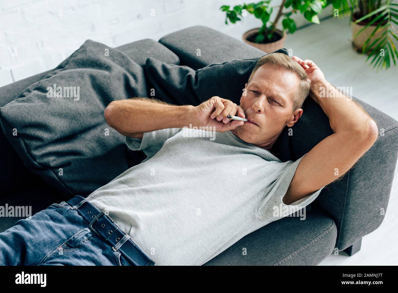 handsome man smoking blunt with medical cannabis in apartment Stock ...