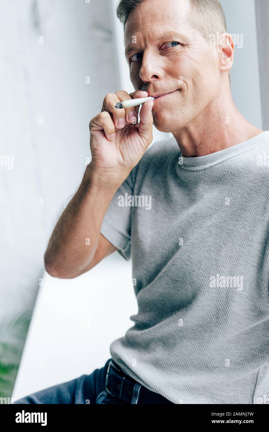 handsome man smoking blunt with medical cannabis in apartment Stock ...