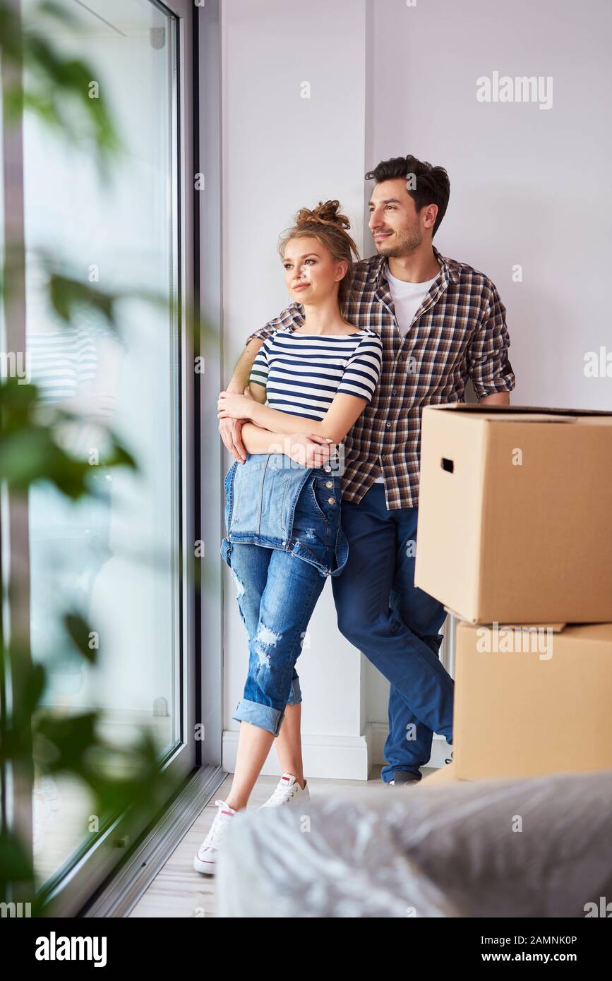 Young couple looking through window in their apartment Stock Photo - Alamy