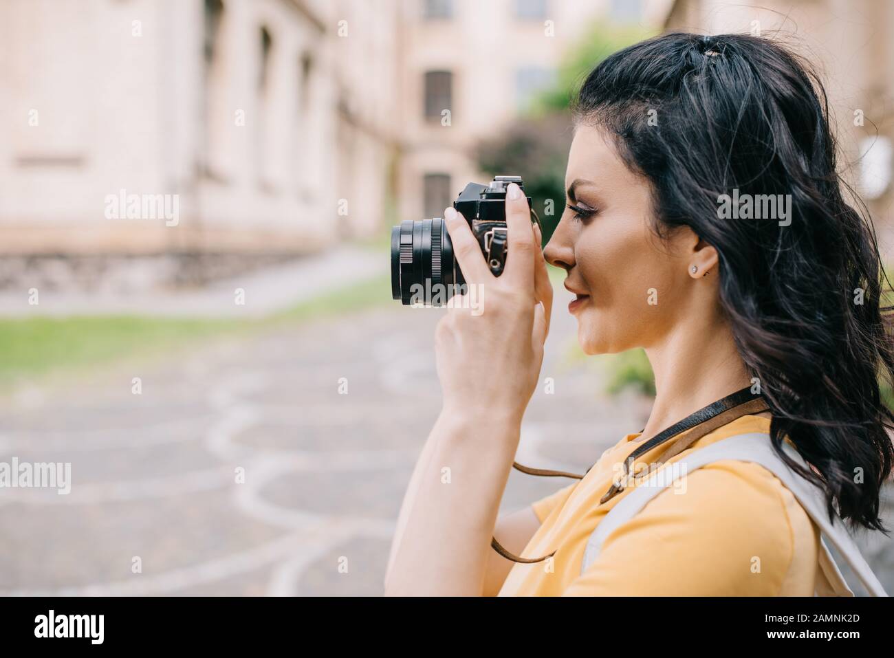 side view of attractive girl holding digital camera while taking photo ...