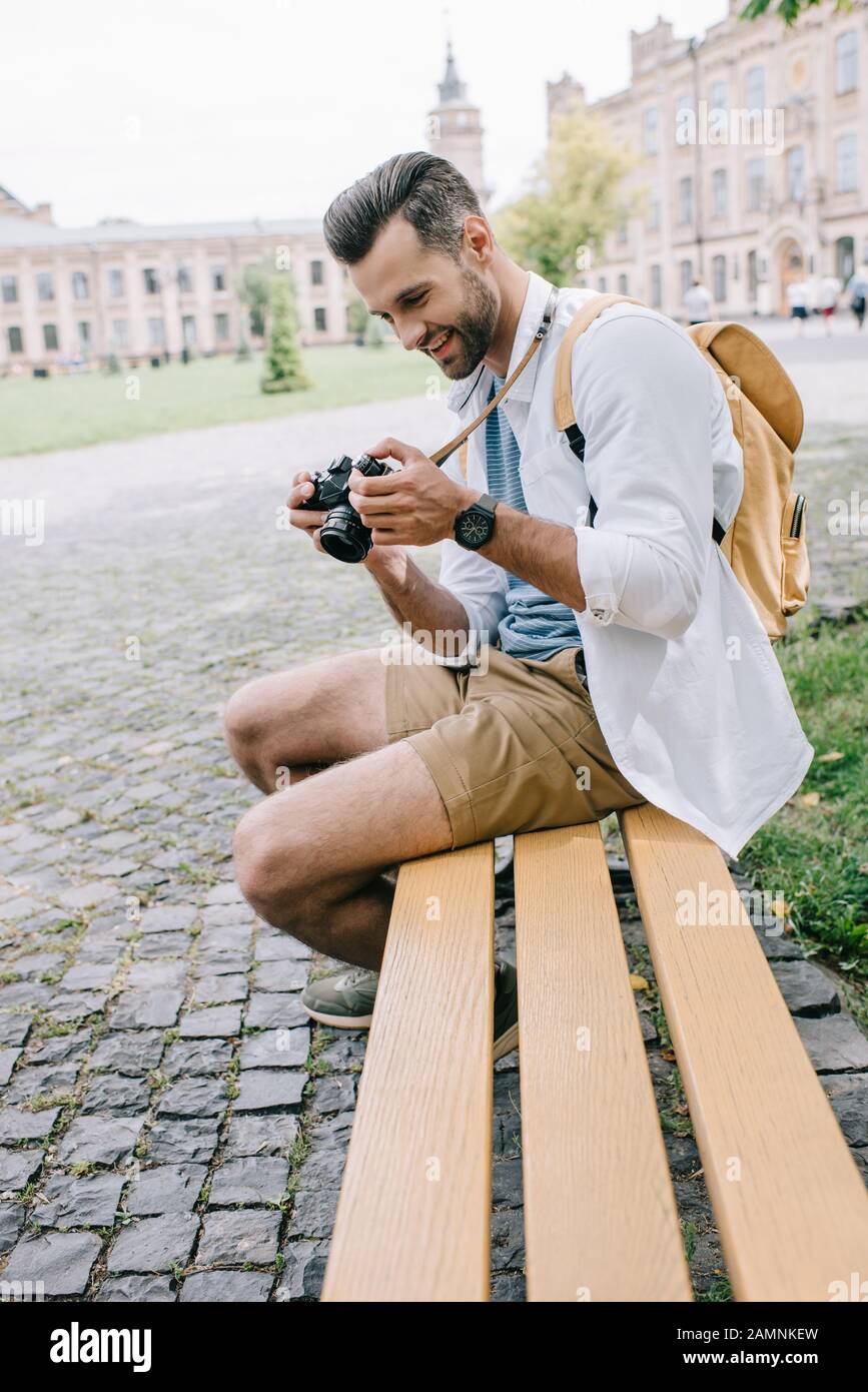 selective focus of happy man looking at digital camera while sitting on ...