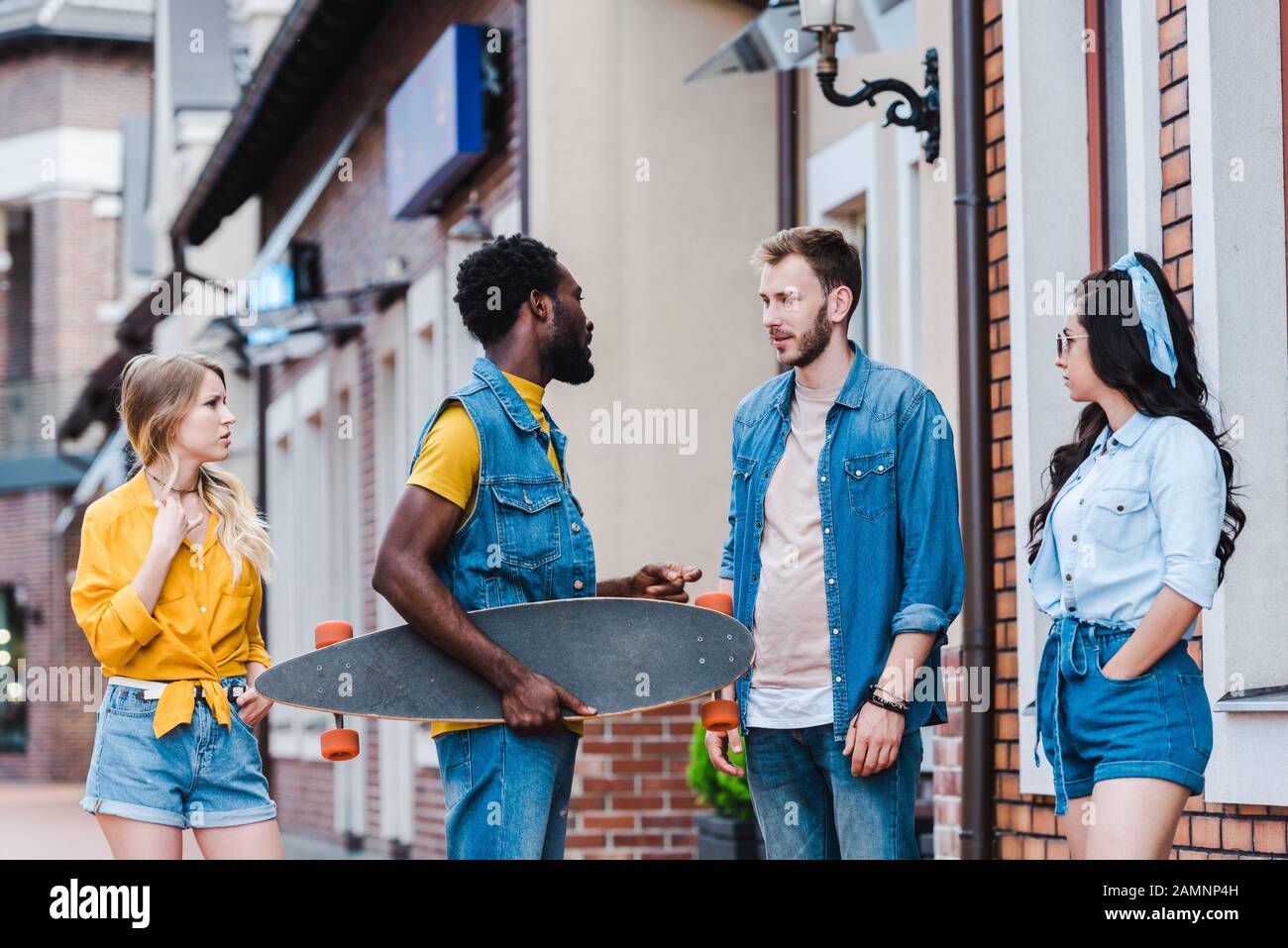 handsome multicultural men talking while standing near attractive girls ...