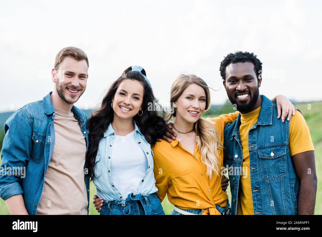 group of happy multicultural friends standing together and looking at ...