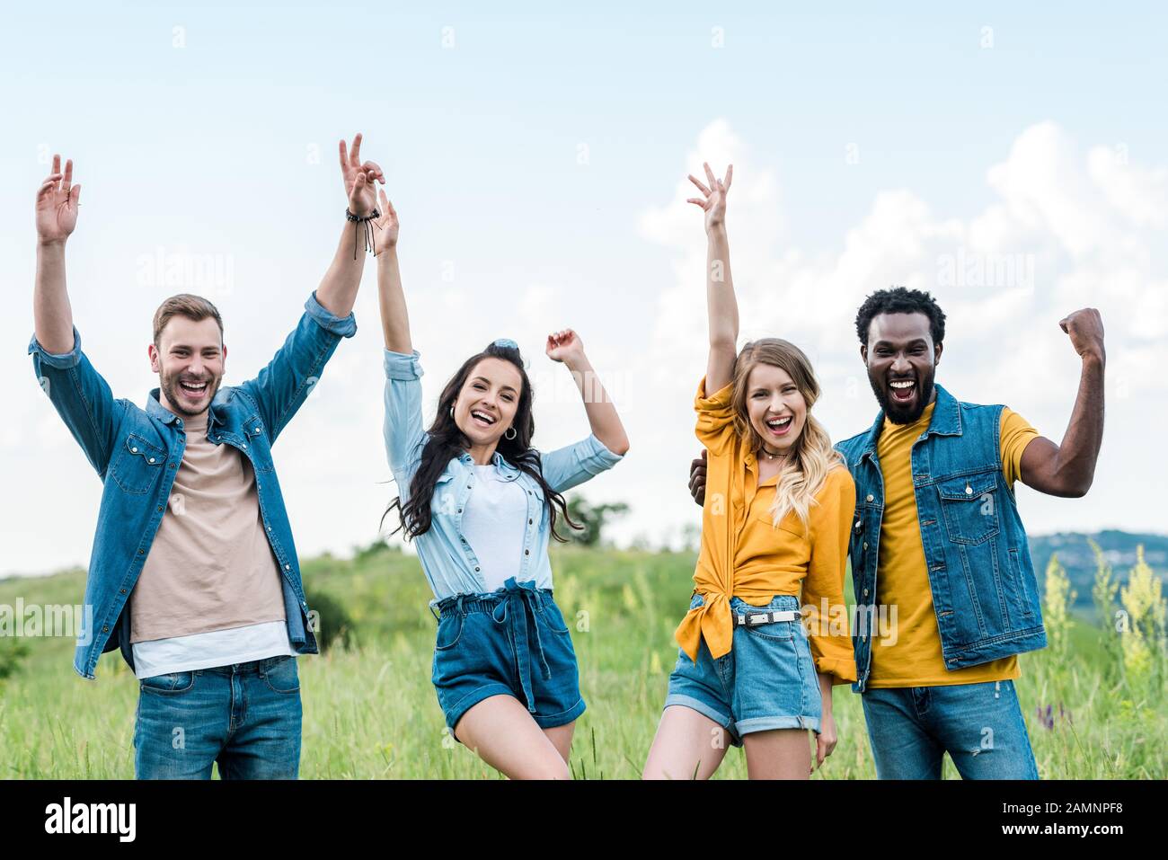 happy multicultural friends standing together and gesturing while ...