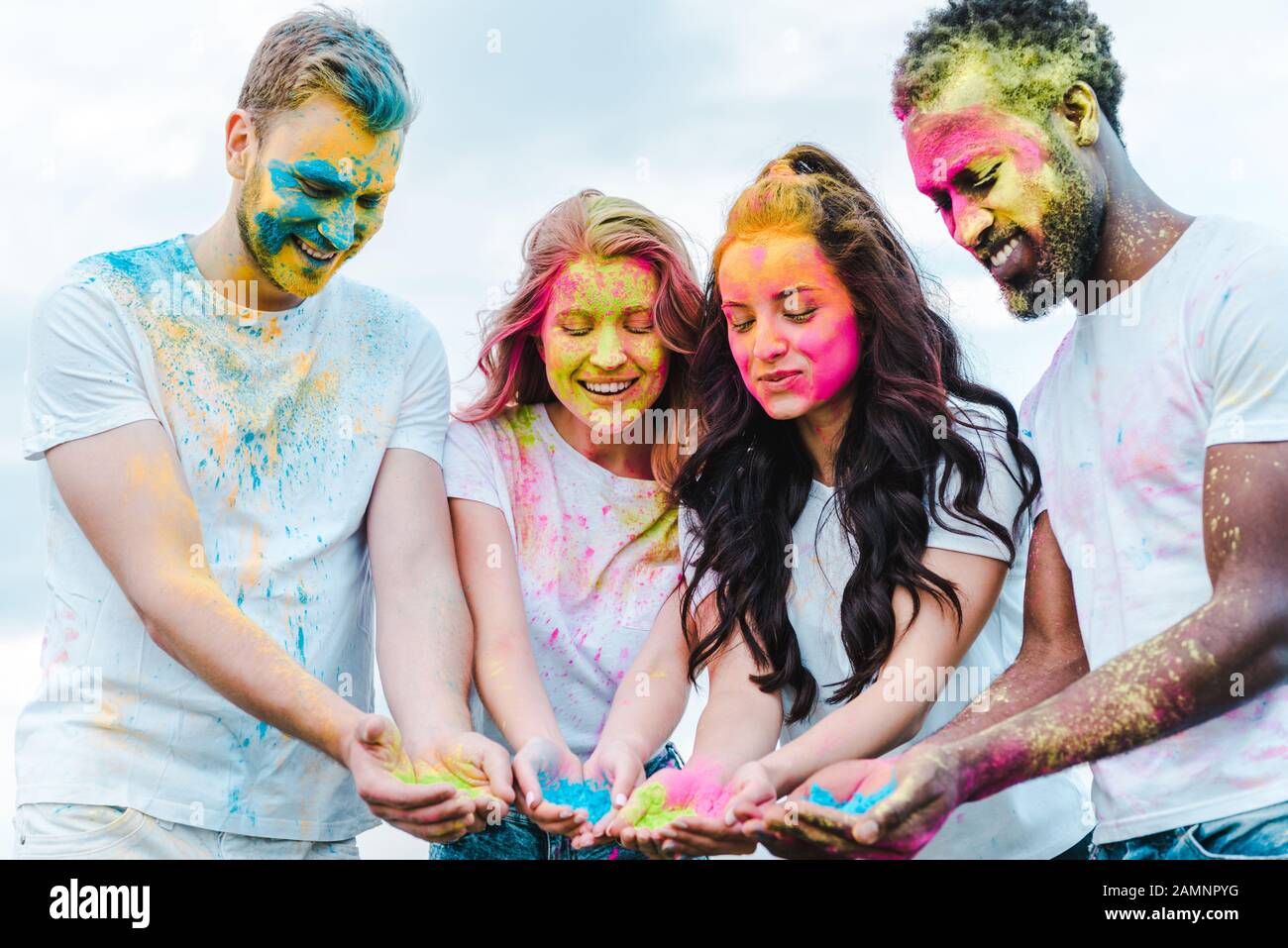 happy girls near multicultural men holding holi paints Stock Photo - Alamy