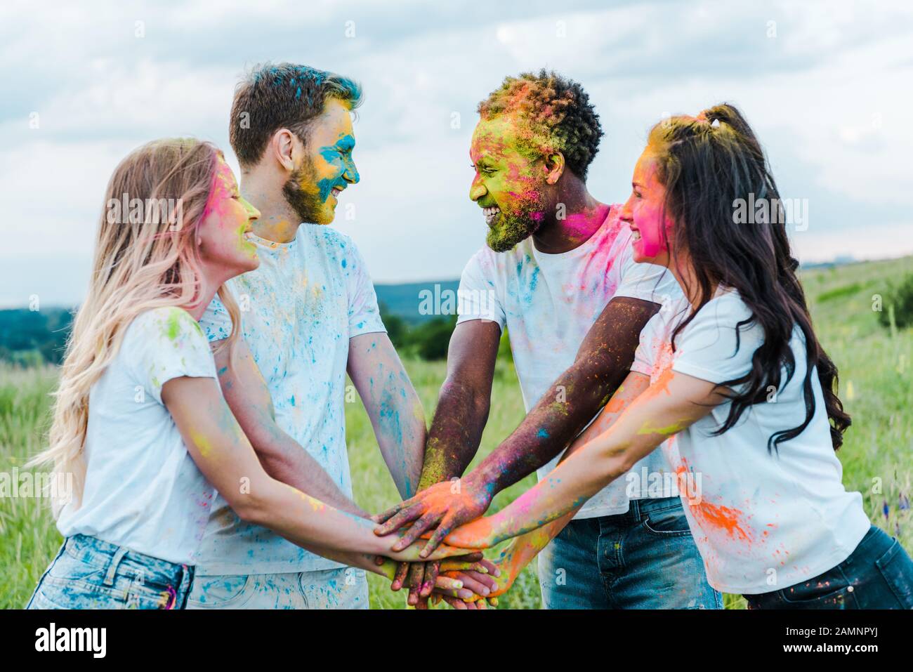 happy girls and multicultural men with colorful holi paints on faces ...