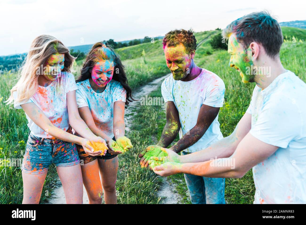 happy multicultural friends holding colorful holi paints in hands Stock ...