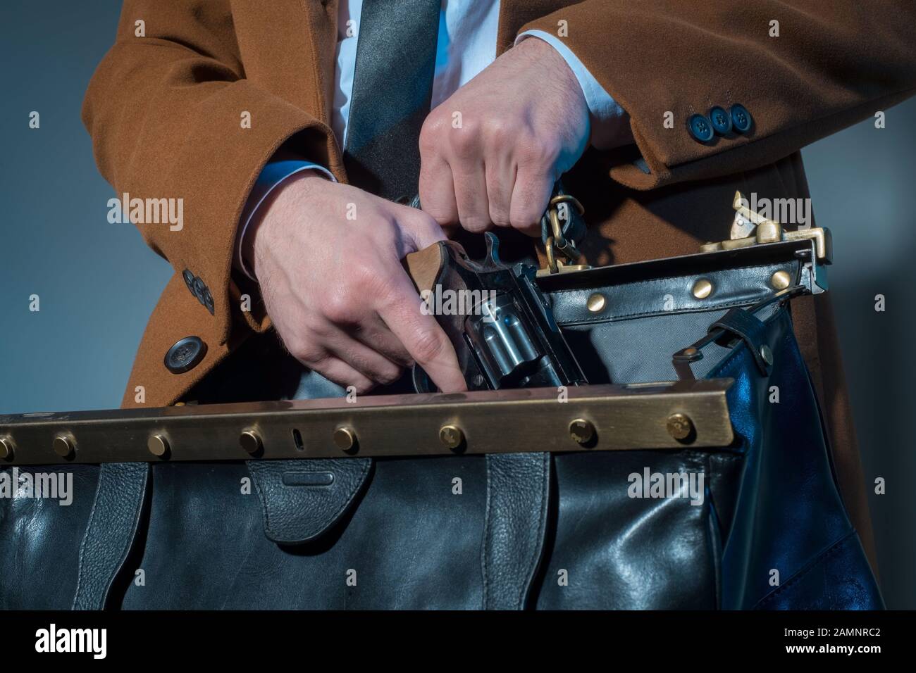 Close-up of a leather bag from which a man takes a gun. The concept of ...