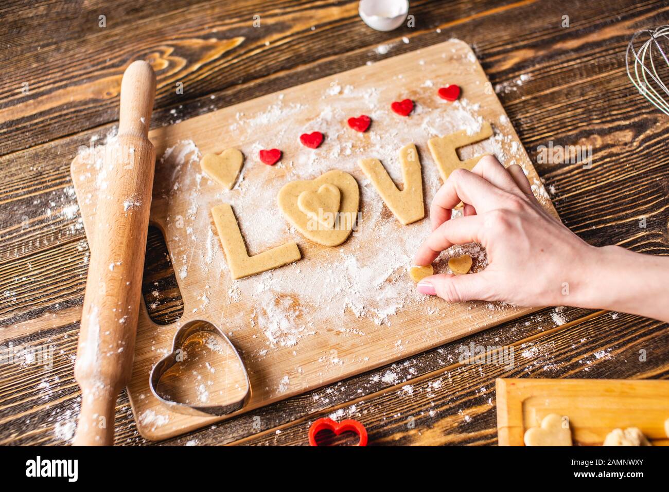 Cooking cookies from the dough in the shape of a heart and the word ...
