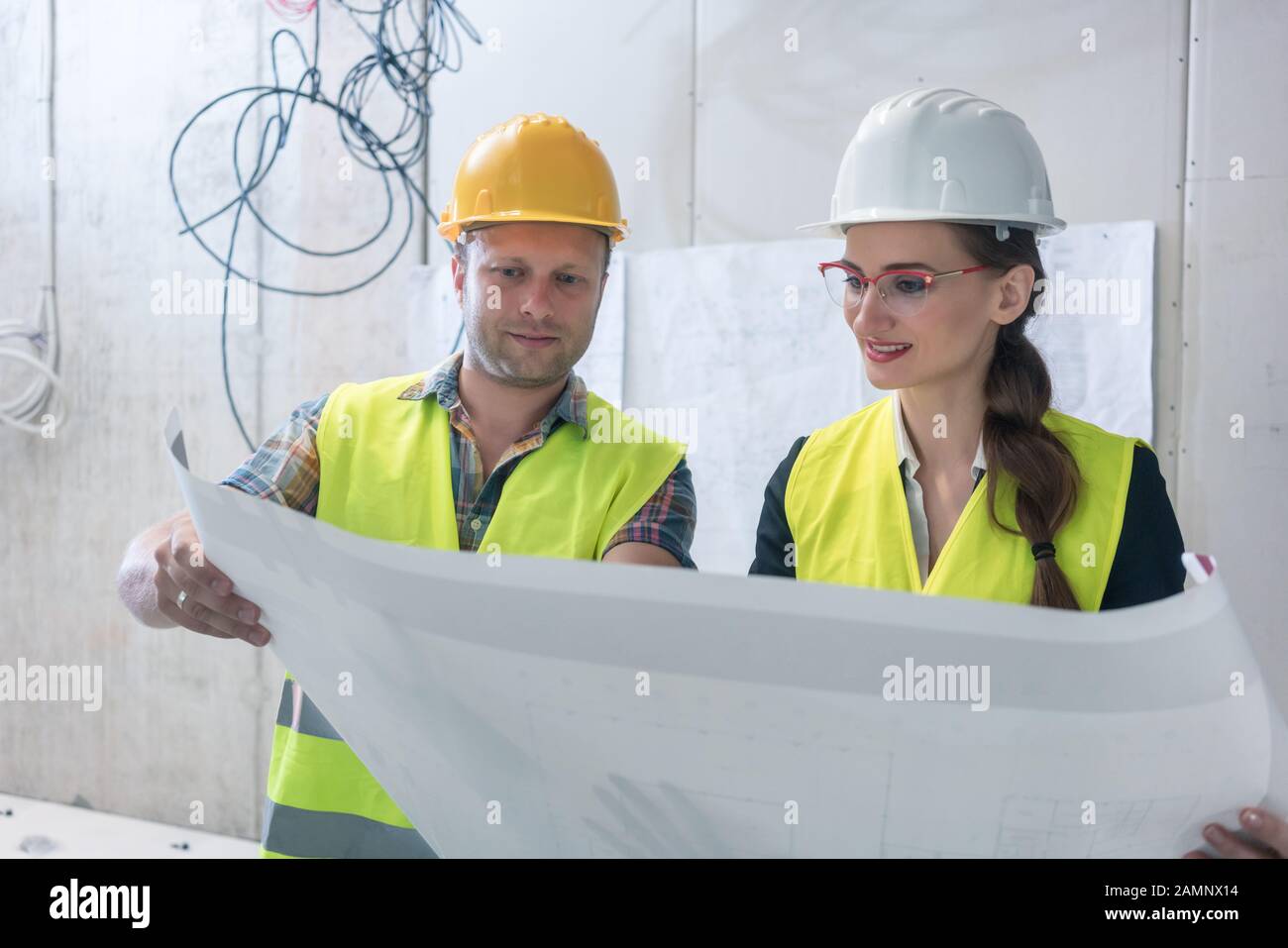 Construction worker and architect reading plan Stock Photo - Alamy