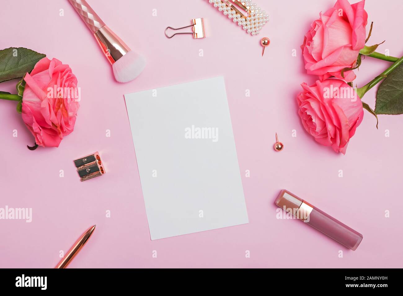 Blank paper card, feminine accessories and roses on pink table, top ...