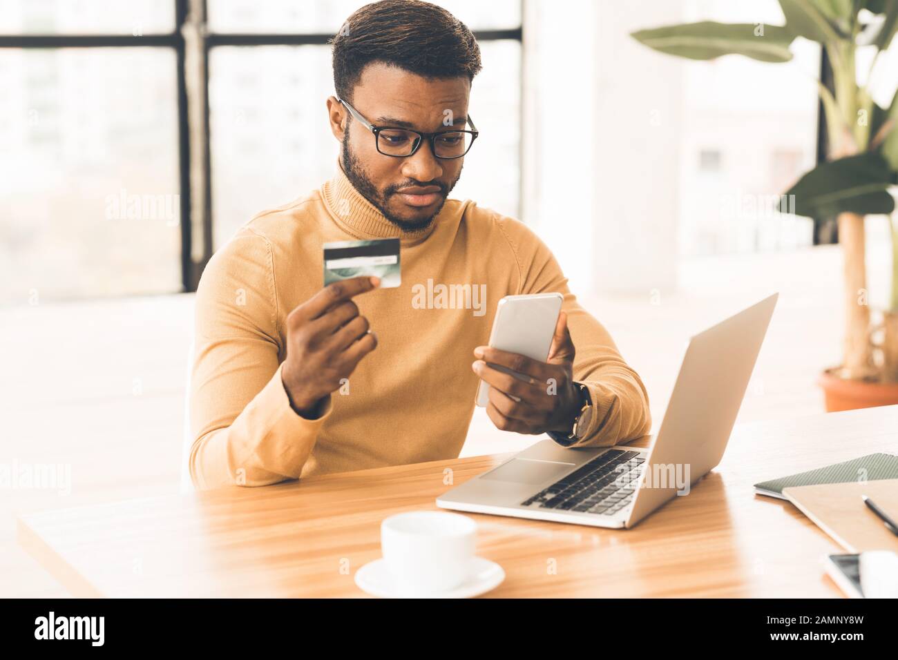 Black manager making purchases using computer and phone Stock Photo - Alamy