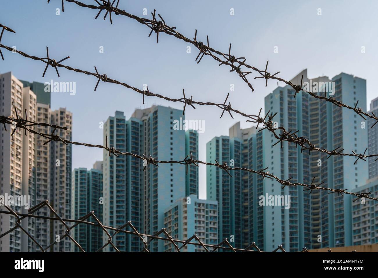 barbed wire fence closeup with buildings in background Stock Photo - Alamy