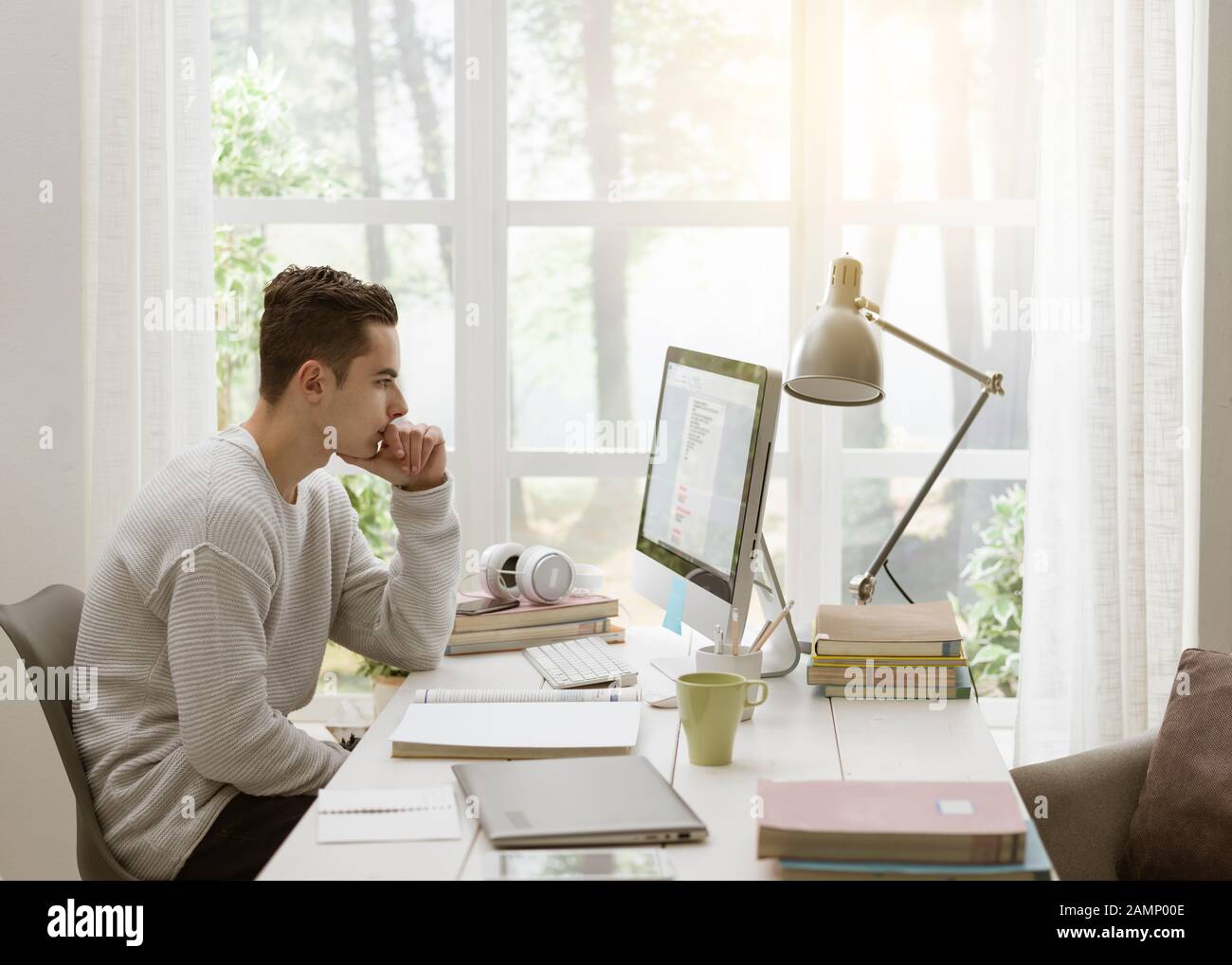 Smart college student using computer at home, he is studying and ...