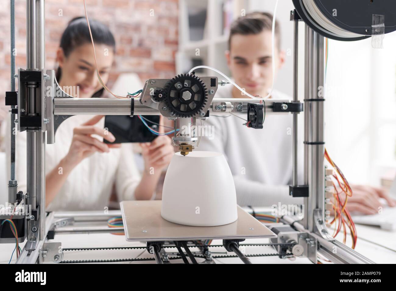 Engineering students printing prototype models using a 3D printer, the ...