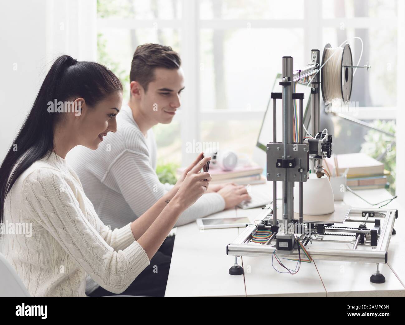 Engineering students printing prototype models using a 3D printer, the ...