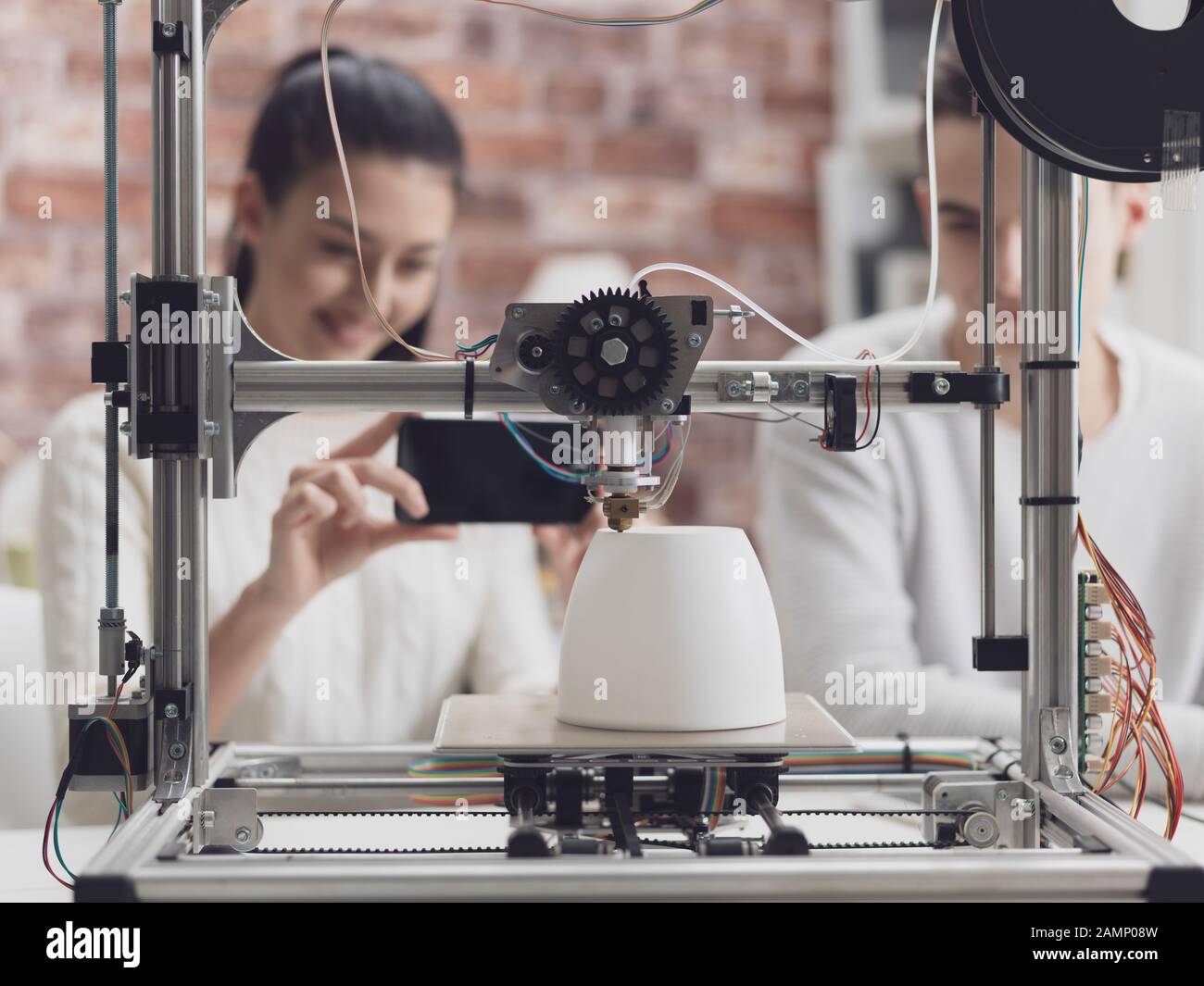 Engineering students printing prototype models using a 3D printer, the ...