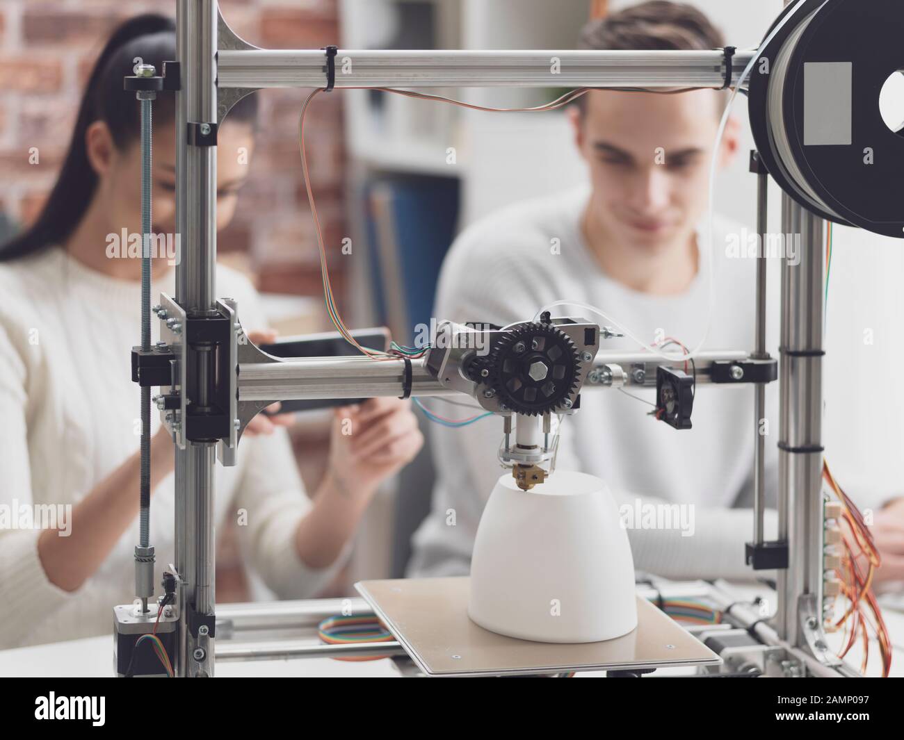 Engineering students printing prototype models using a 3D printer, the ...