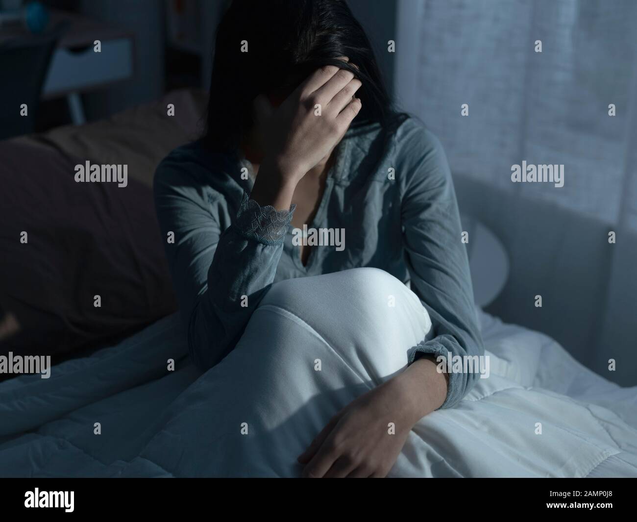 Sad depressed woman lying in bed late at night, she is suffering from ...