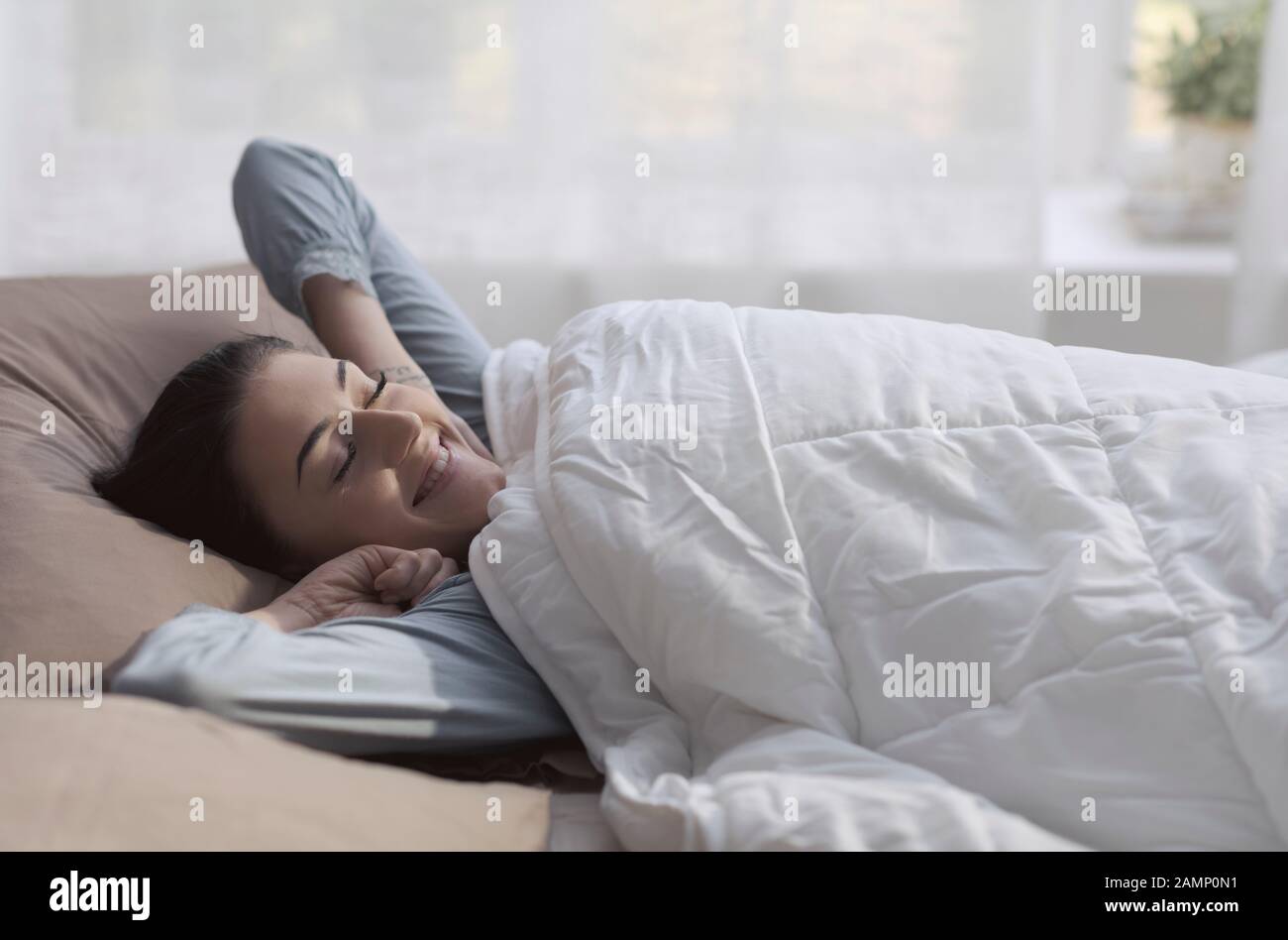 Happy relaxed woman waking up early in the morning and stretching her ...