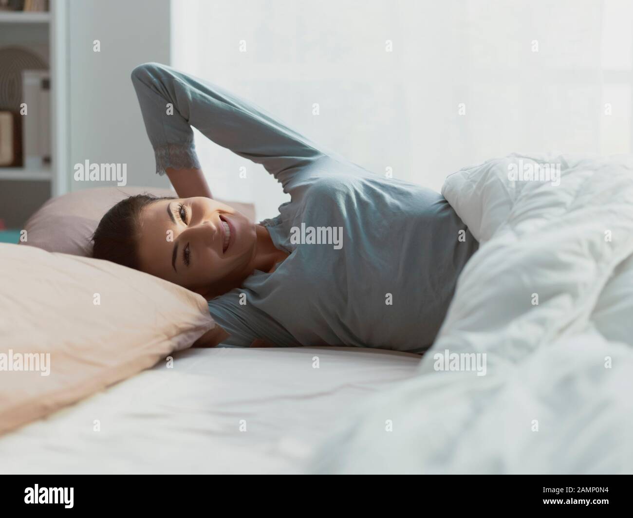 Happy relaxed woman waking up early in the morning and stretching her ...
