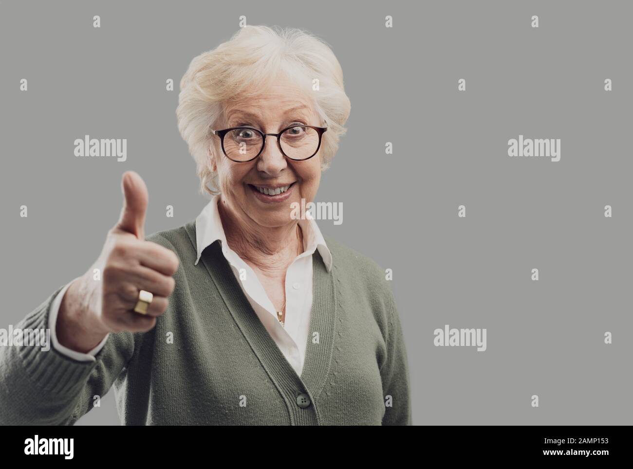 Cheerful senior lady giving a thumbs up and smiling at camera, approval ...
