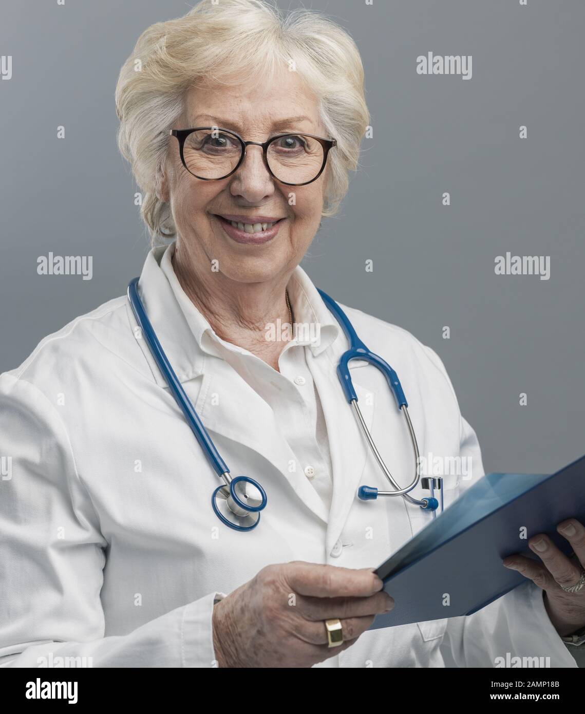 Confident senior female doctor posing and smiling, she is holding a ...
