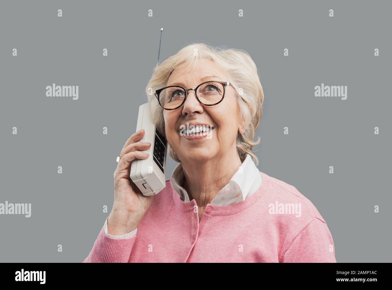 Happy senior woman talking with an old cordless telephone, she is ...