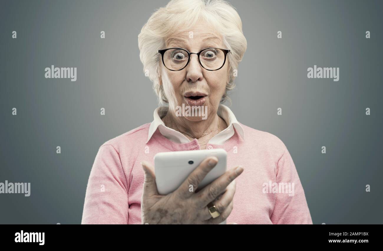 Happy surprised senior woman using a digital tablet, she has received ...