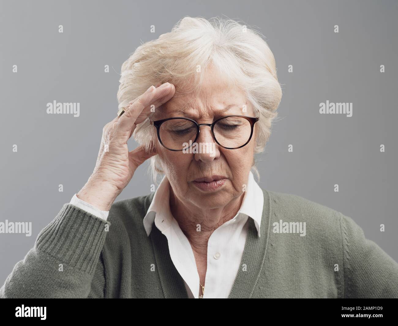 Old woman having a bad headache, she is touching her forehead and ...