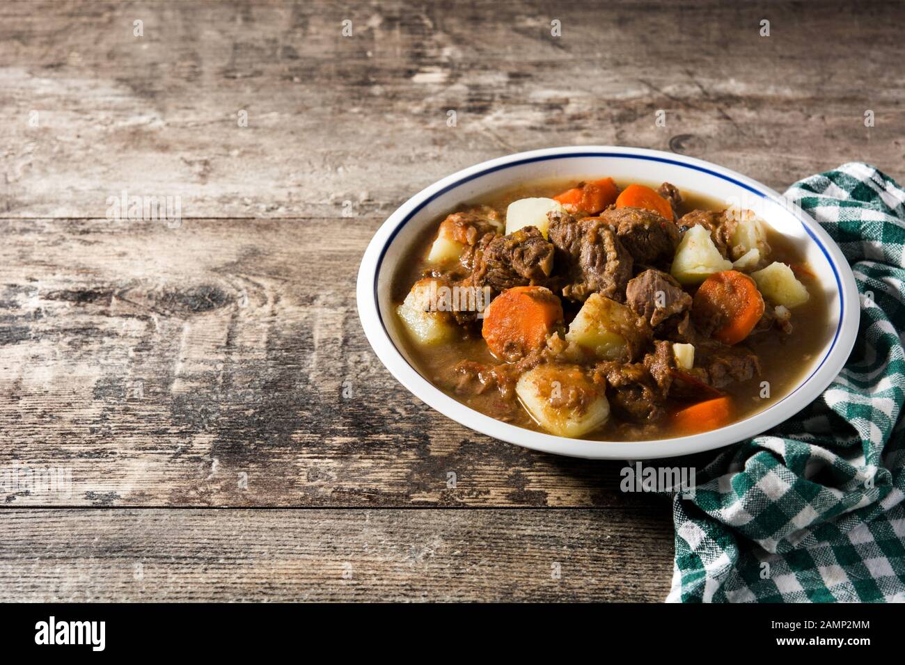 Irish beef stew with carrots and potatoes on wooden table. Copy space ...