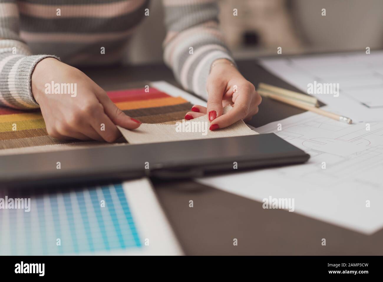 Professional creative decorator working at desk and choosing fabric ...