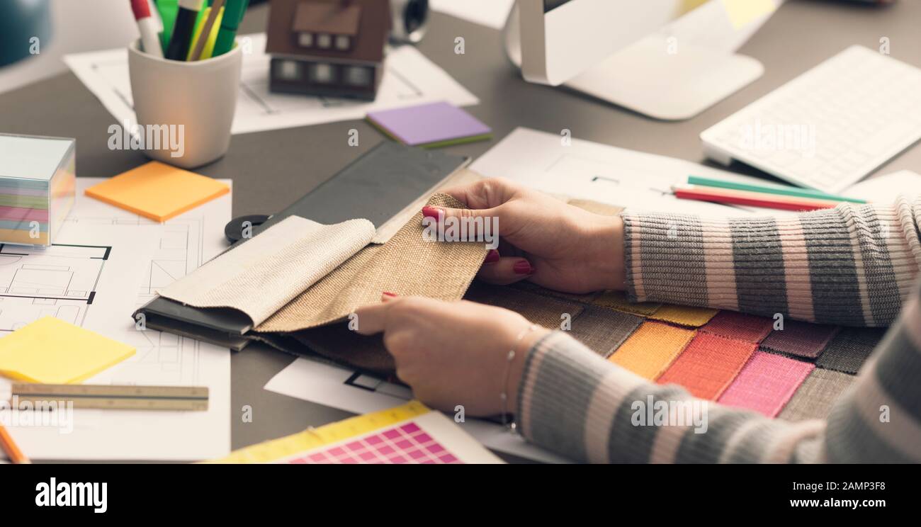 Professional creative decorator working at desk and choosing fabric ...