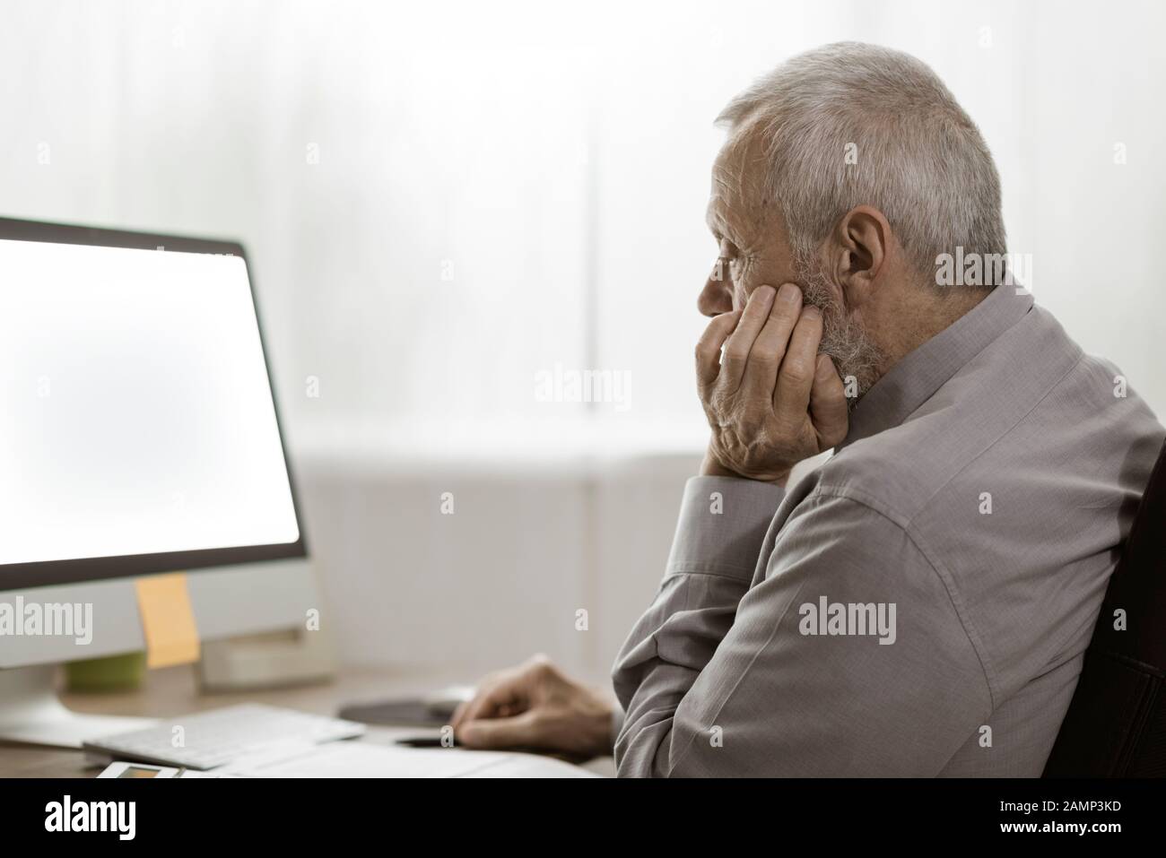 Senior man staring at the computer screen, he is web browsing, elderly ...