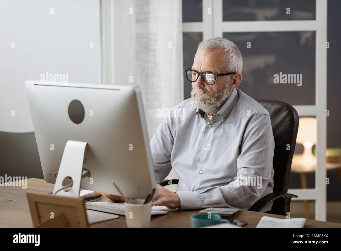 Senior retired man sitting ad desk and working with a computer, elderly ...
