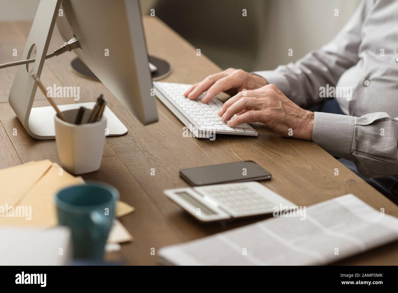 Senior retired man sitting ad desk and working with a computer, elderly ...
