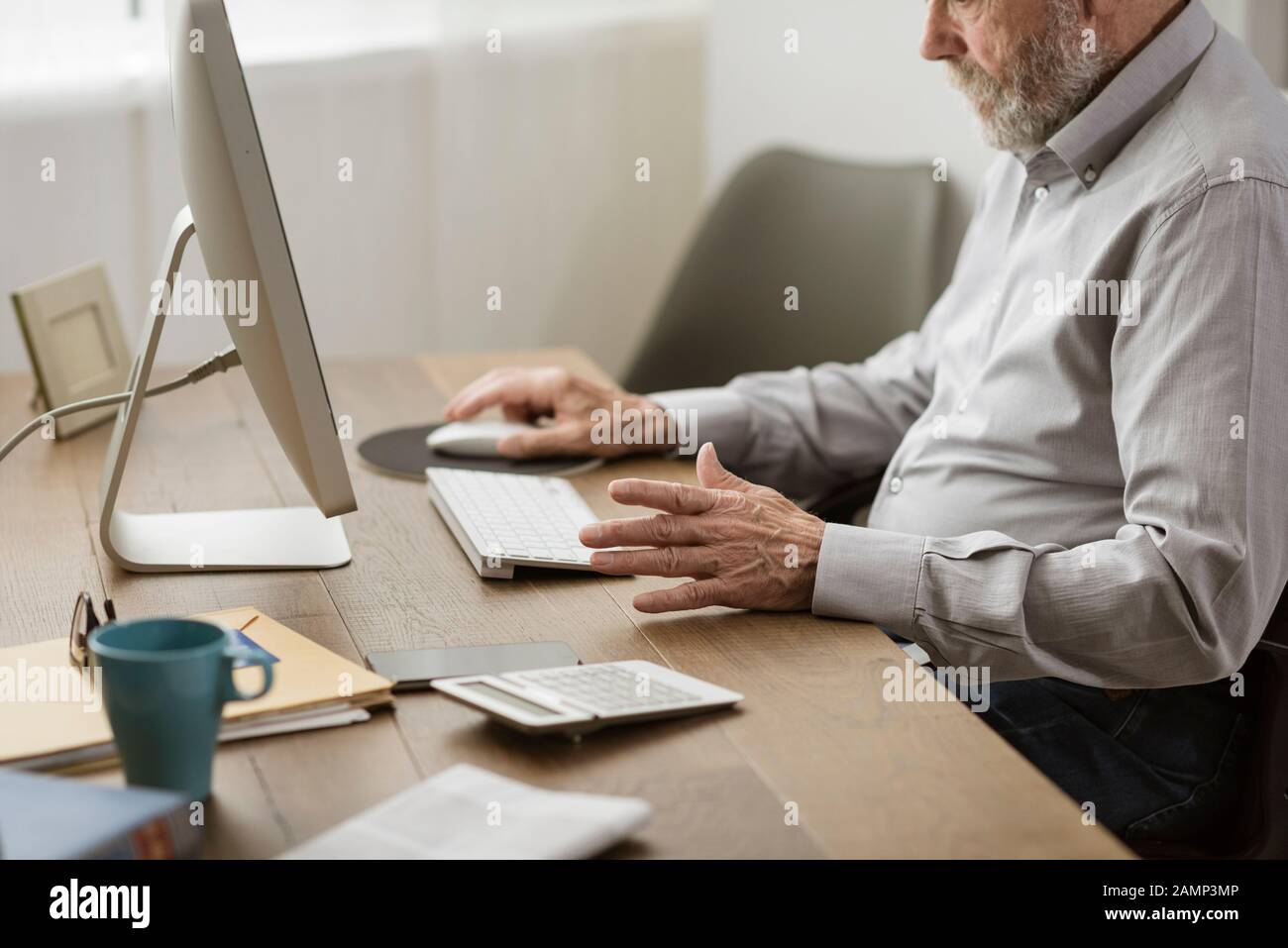 Senior man using his computer at home, he is having difficulties ...