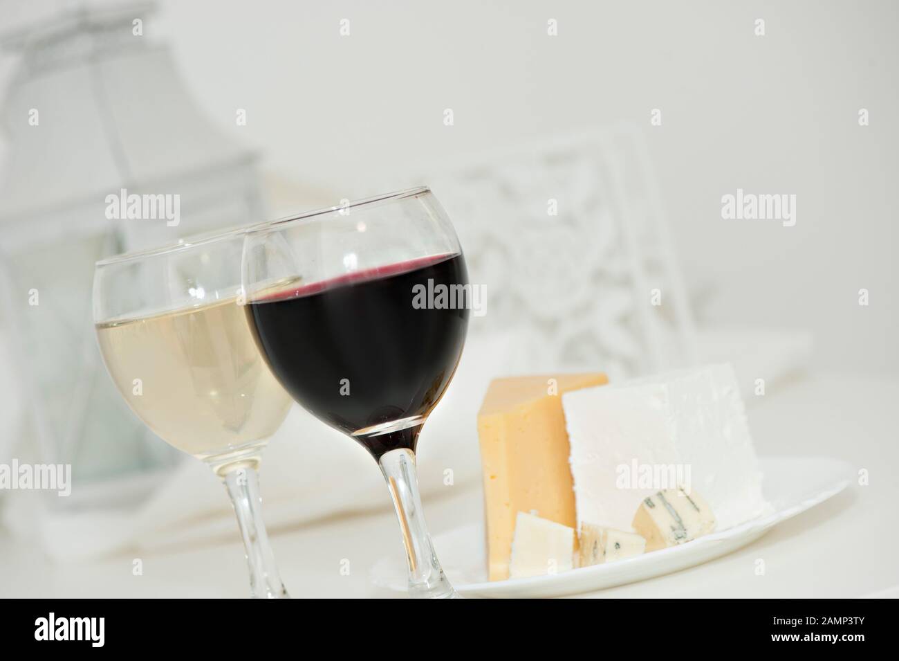 Glasses with red and white wine and cheese on a plate on a light ...