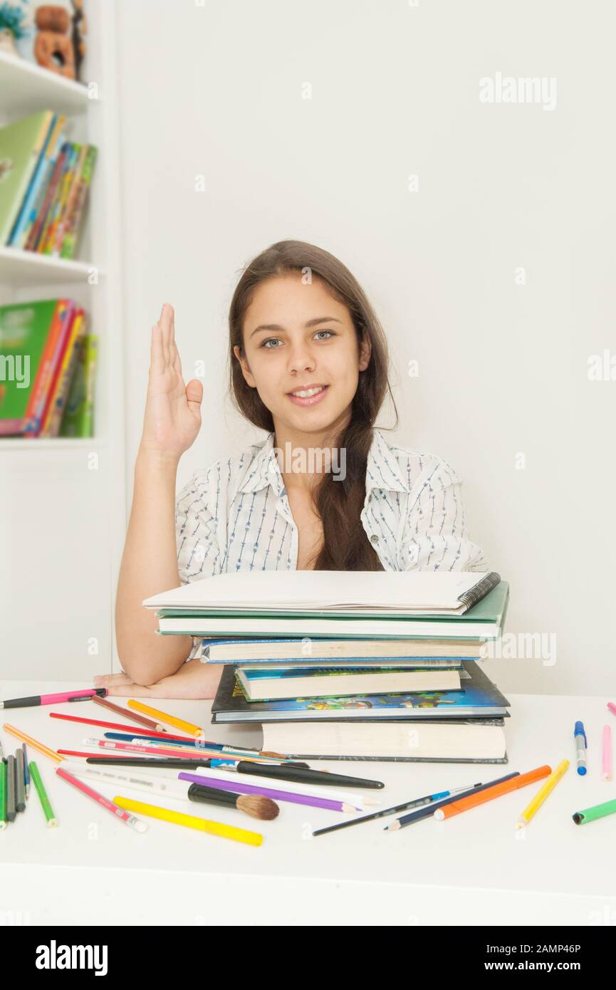 Girl doing homework with a stack of textbooks on the background of ...