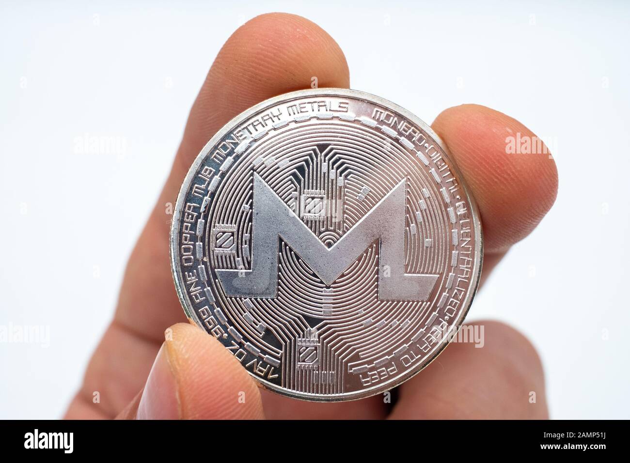Hand holding a Monero cryptocurrency coin in his hand against a white ...