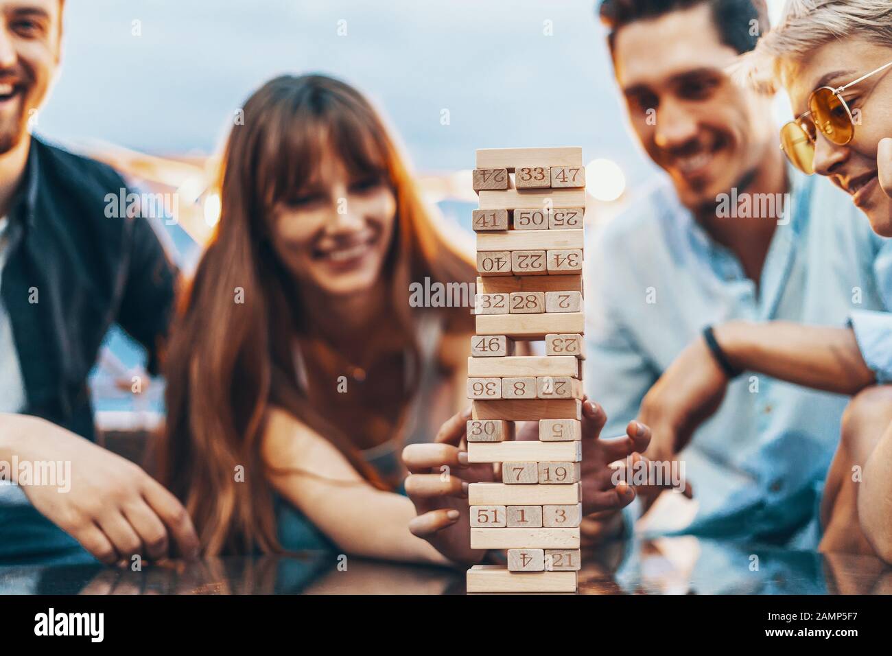 The company of young people playing jenga. Young friends at sunset on ...
