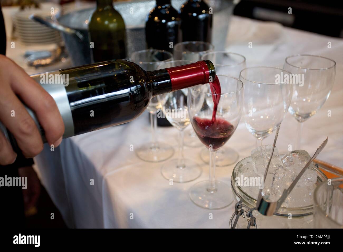 Close-up shot of a waiter pouring a glass of red wine at a social event ...