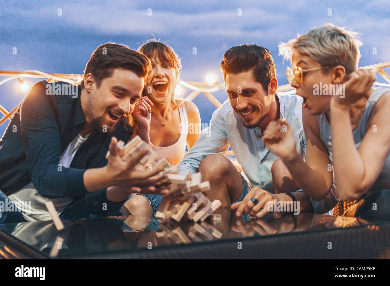 The company of young people playing jenga. Young friends at sunset on ...