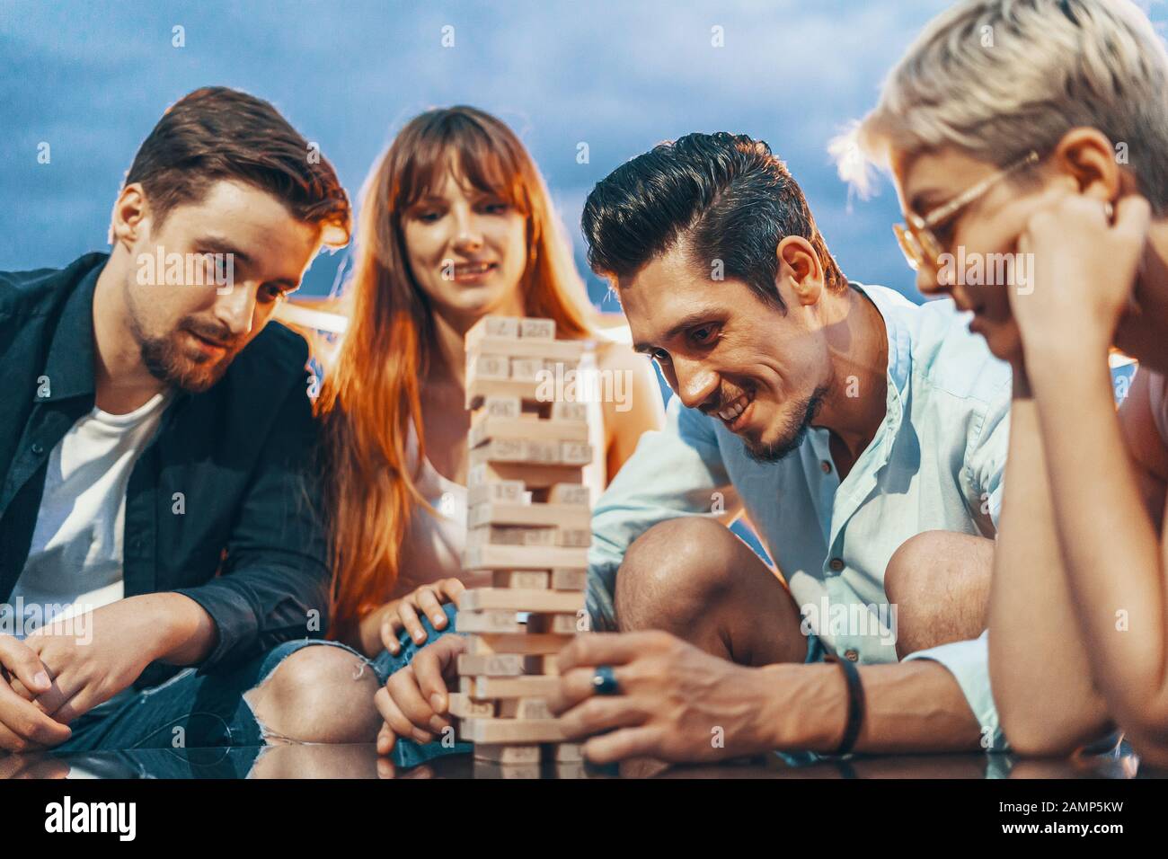 The company of young people playing jenga. Young friends at sunset on ...