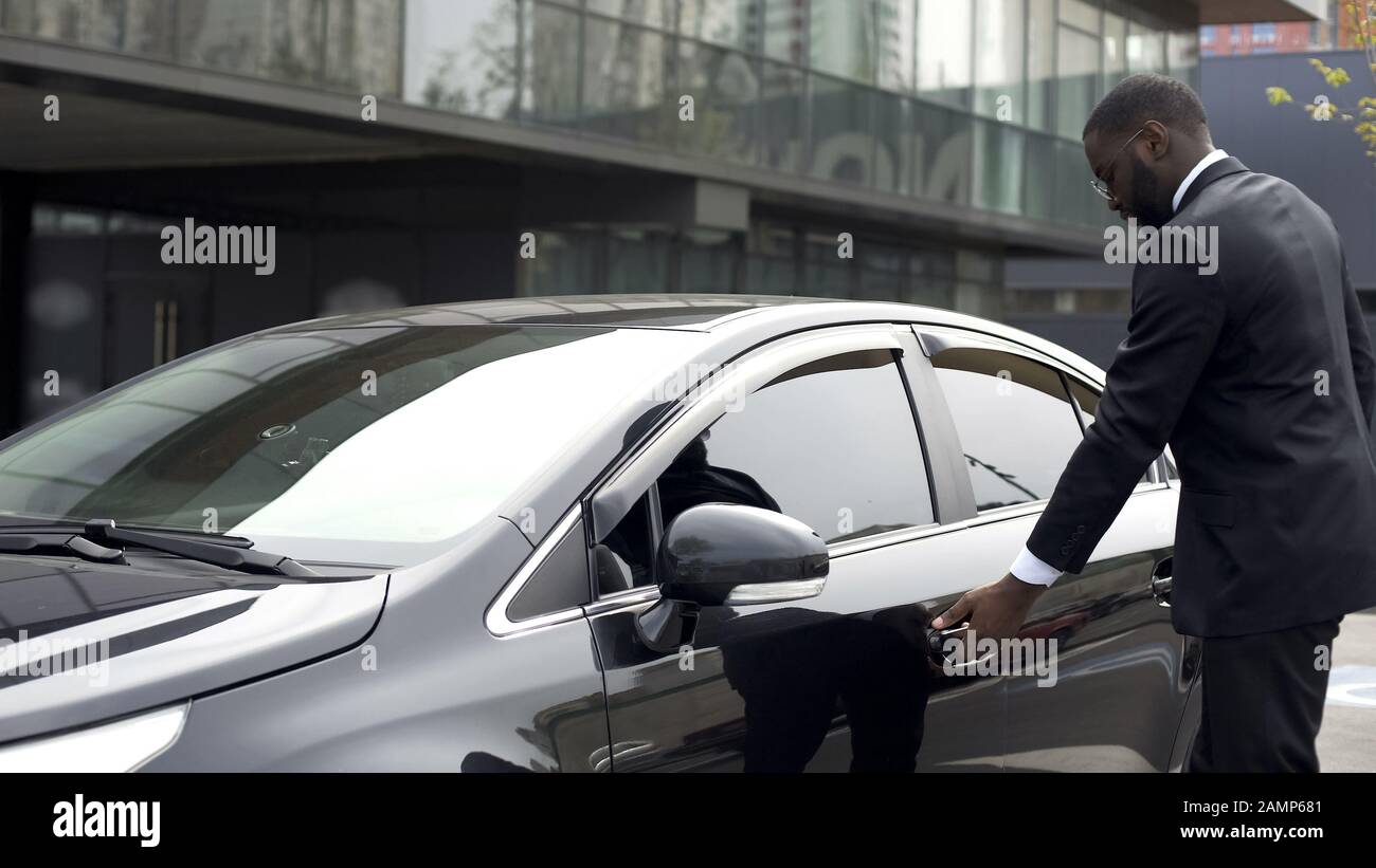 Afro-American man carefully opening door of new car before leaving ...