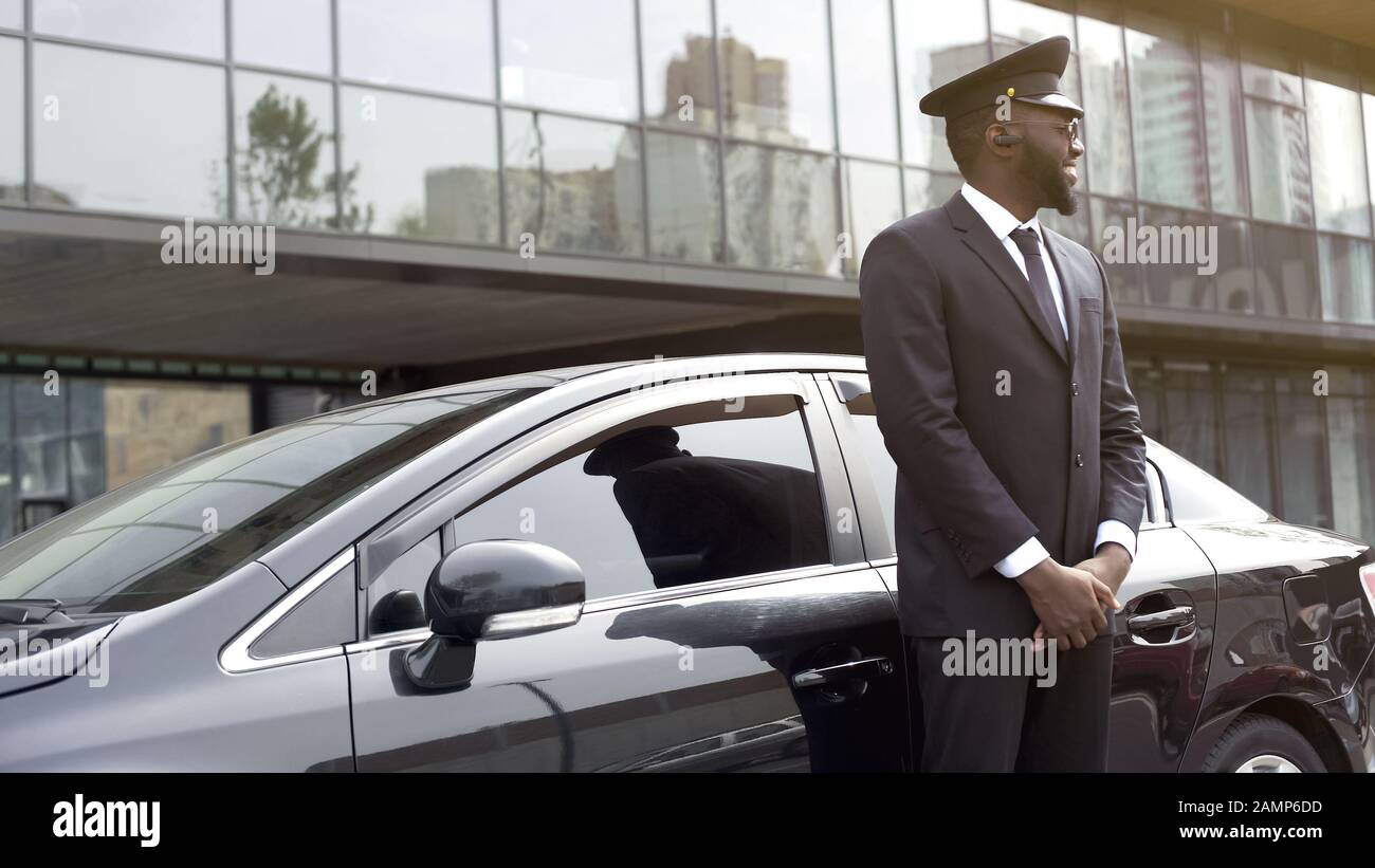 Cheerful Afro-American taxi service driver expecting passengers near ...