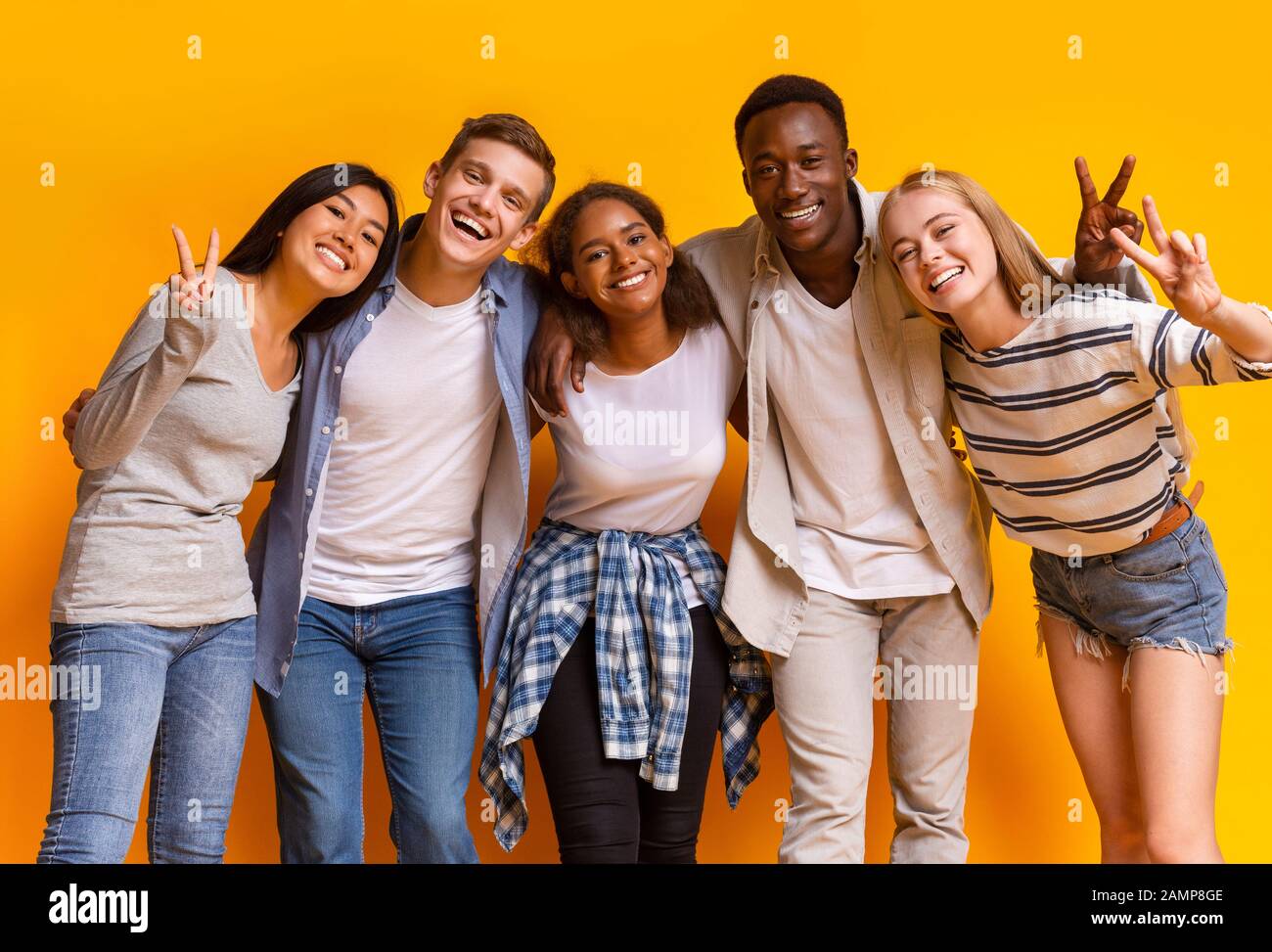 Group of multiracial students smiling and embracing over yellow ...