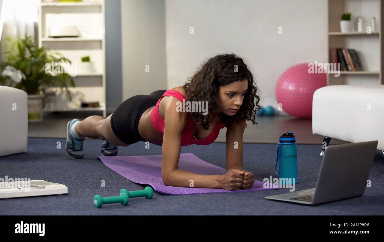 Mixed race young woman doing online workout in front of laptop ...