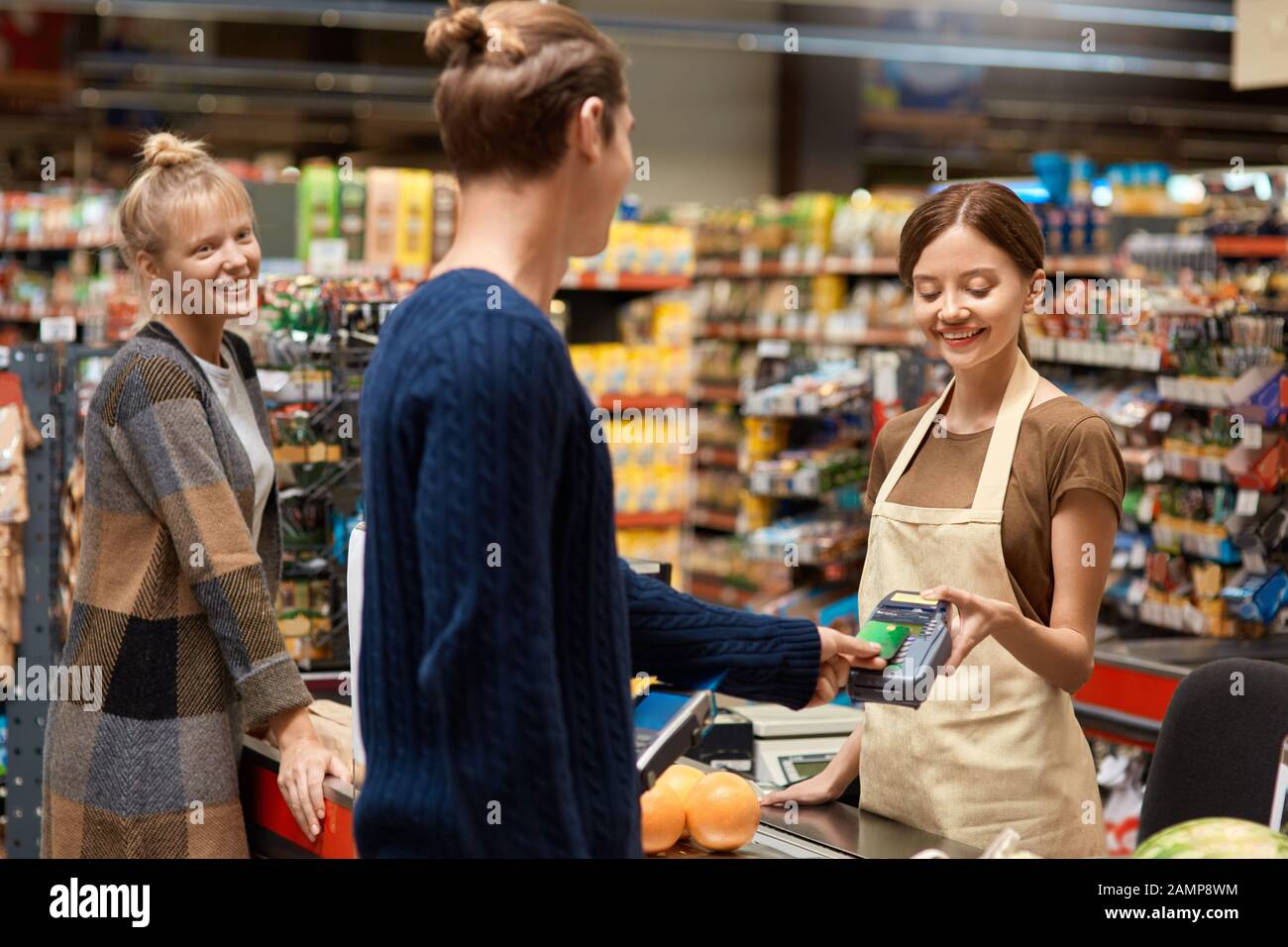 Daily Shopping. Couple at the supermarket standing at checkout ...
